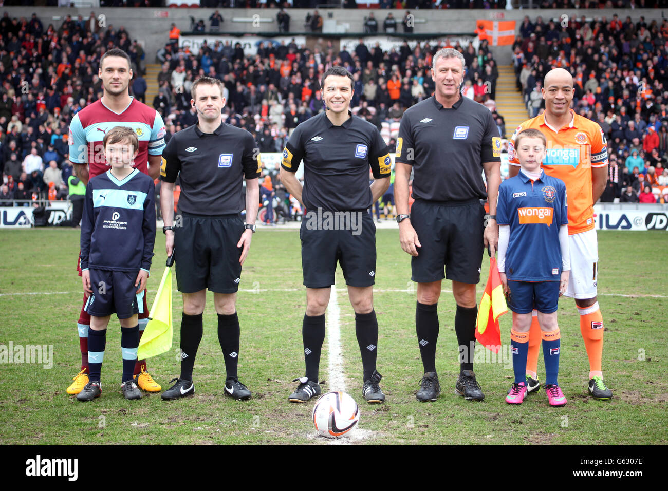 The referee, his assistants and captains and mascots from both teams ...