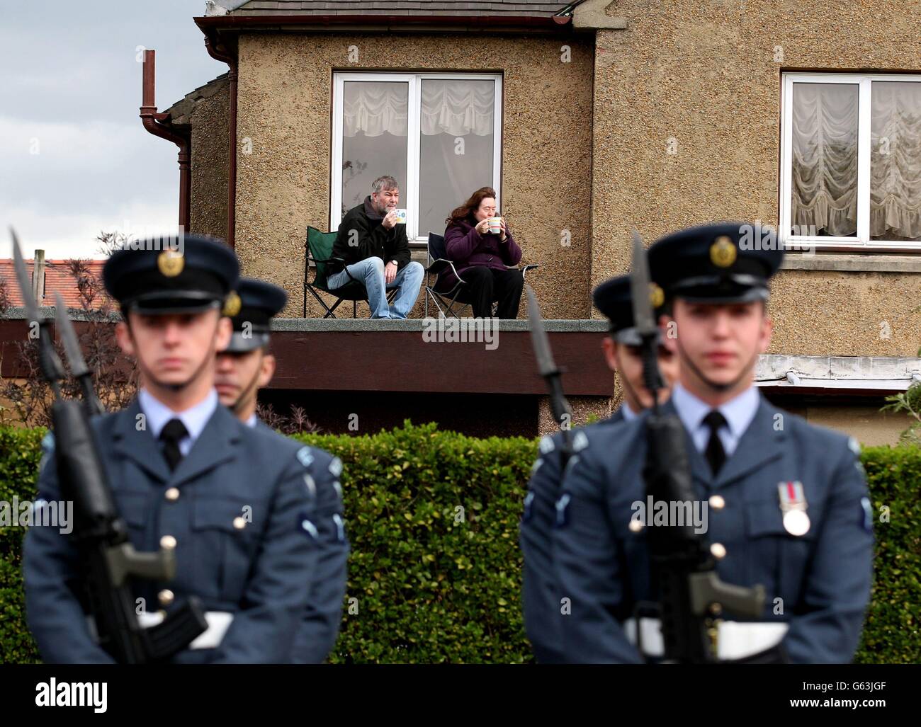 A couple sit on their roof and watch the ceremony as a replica Spitfire ...
