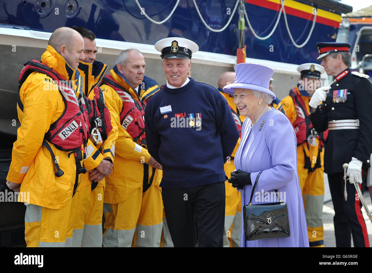 Queen Elizabeth II, accompanied by coxswain Paul Whiston, greets the ...