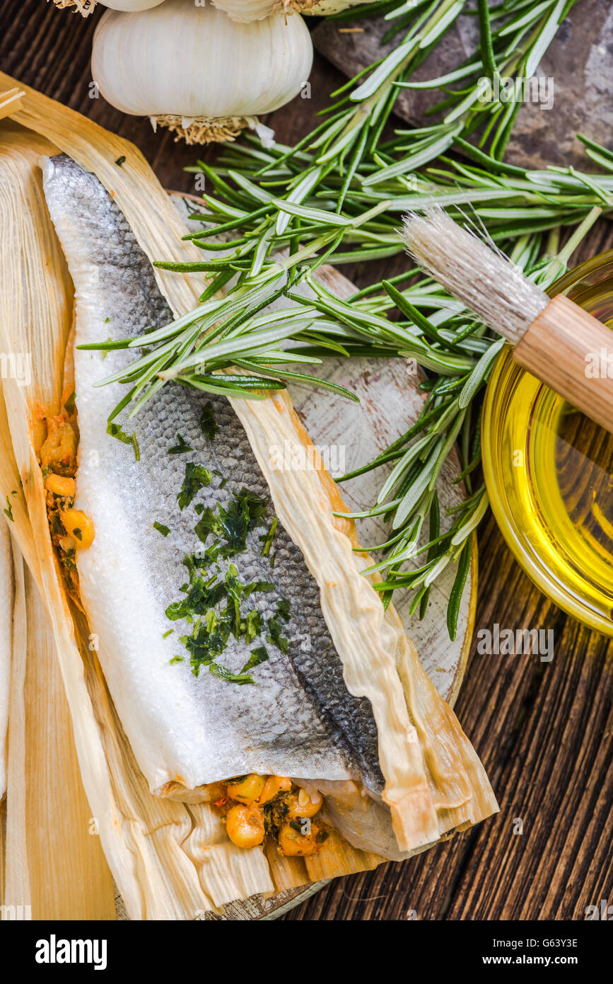 fresh fish wrapped and filled with herbs on wooden table Stock Photo ...