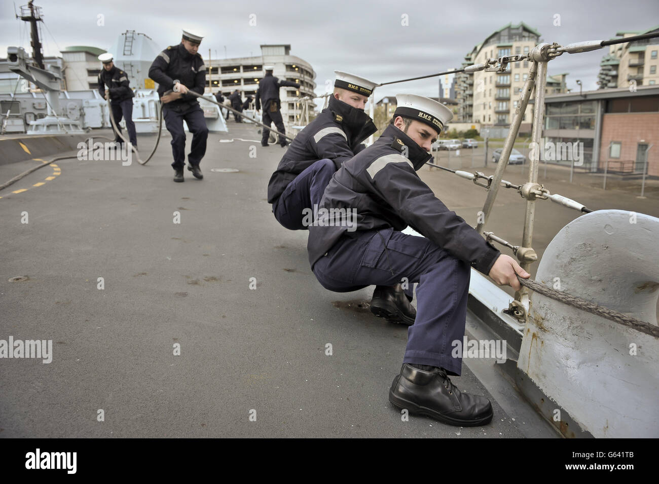 The crew of HMS Edinburgh heave on a berthing line in Leith docks ...
