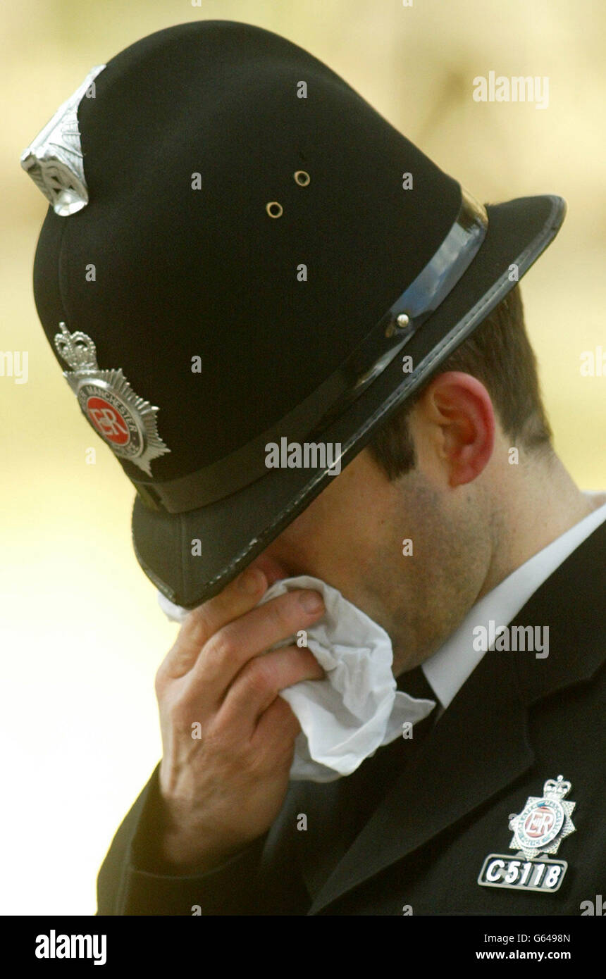 A Police officer shows emotion as the coffin of DC Stephen Oake arrives ...