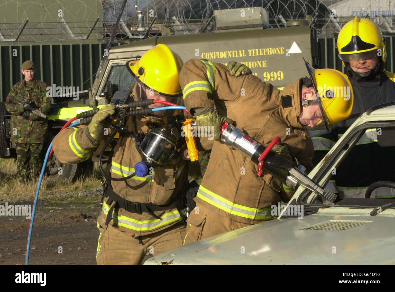 A military fire fighting crew demonstrating a vehicle rescue, in ...