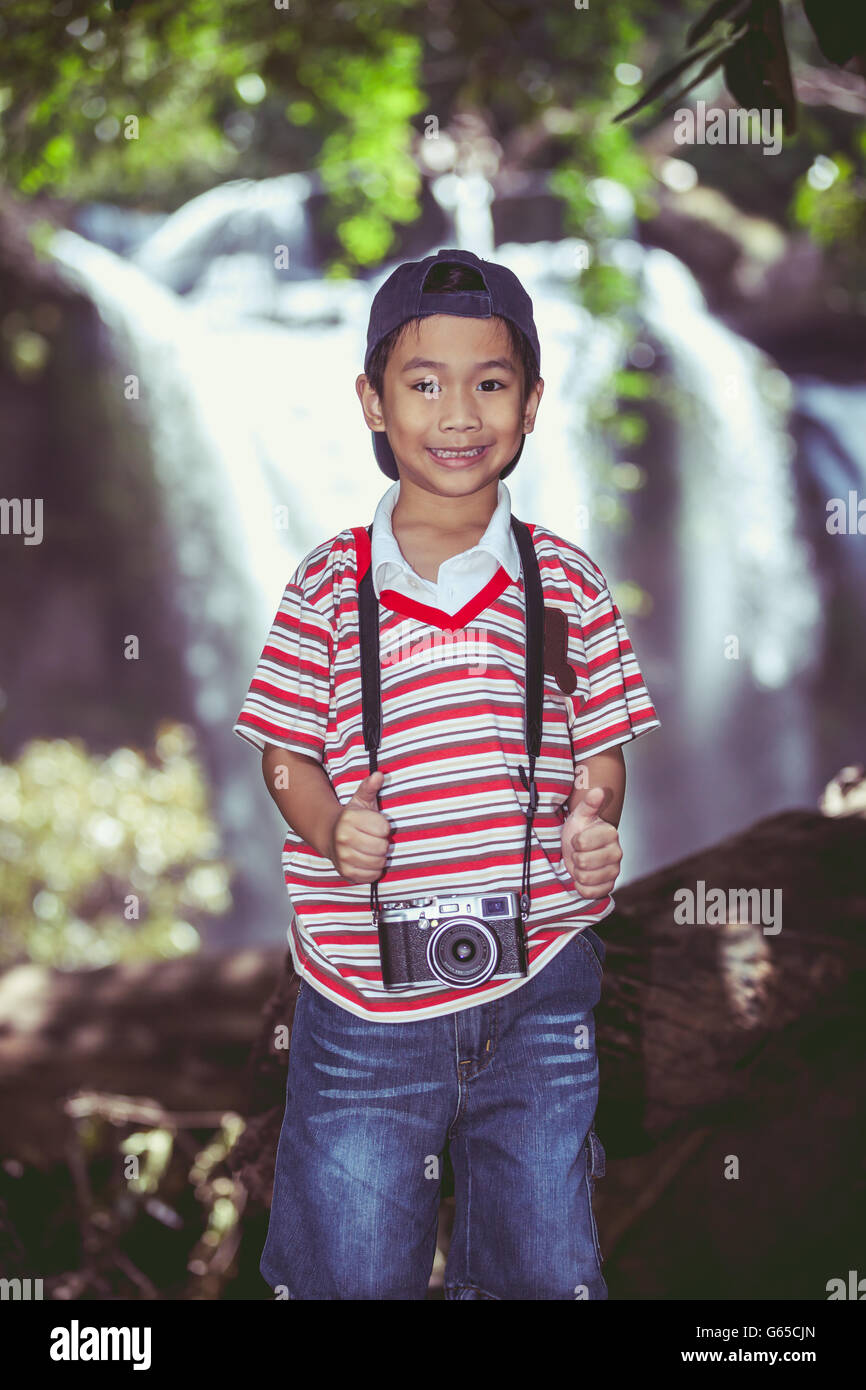 Happy smiling asian child with professional digital camera on blurred ...