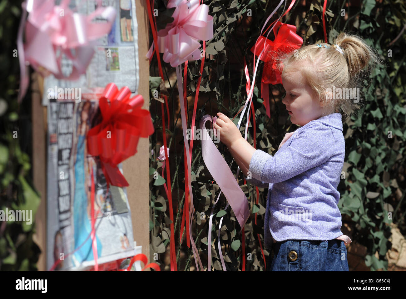 Three year old Ruby Lowe ties ribbons onto a tribute for missing girl ...