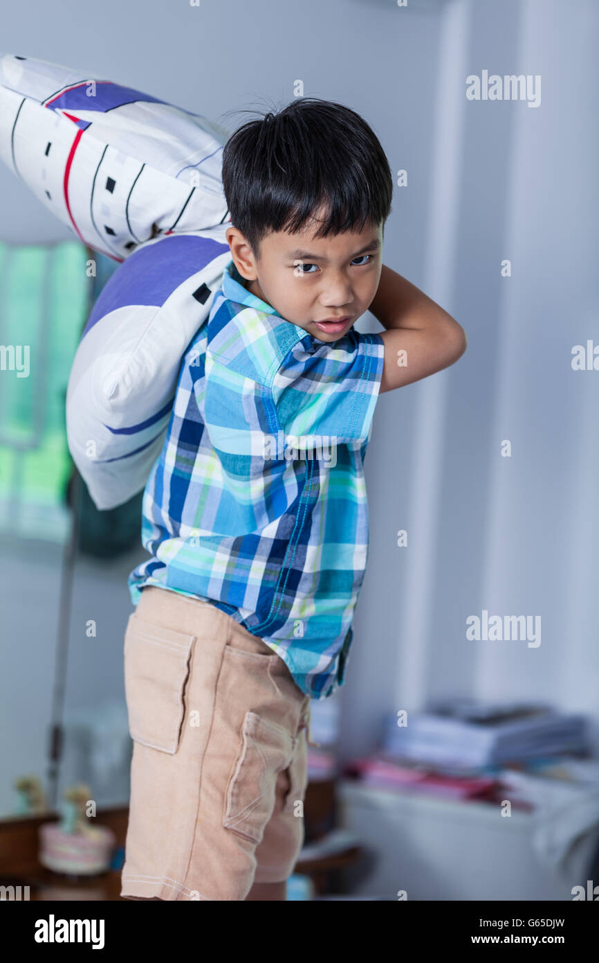An aggressive asian child. Boy looking furious. Kid will throw pillow ...