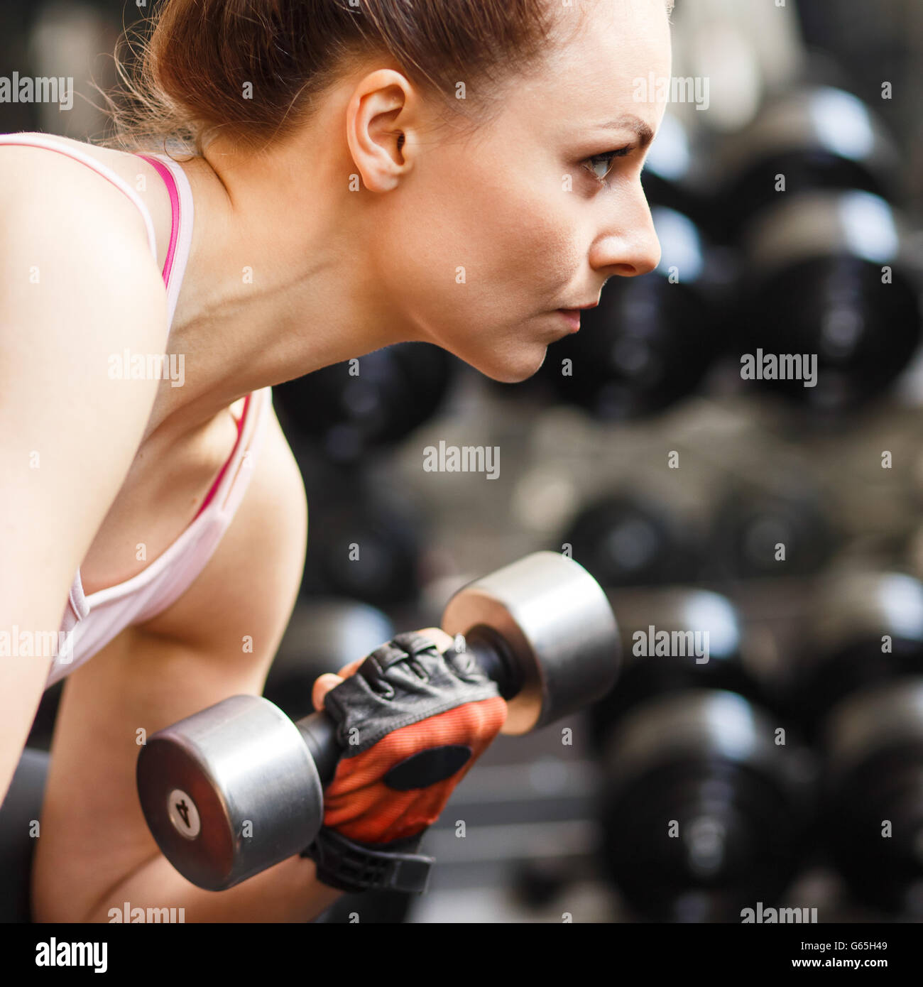 Young confident woman doing biceps curl exercise with dumbbells in ...