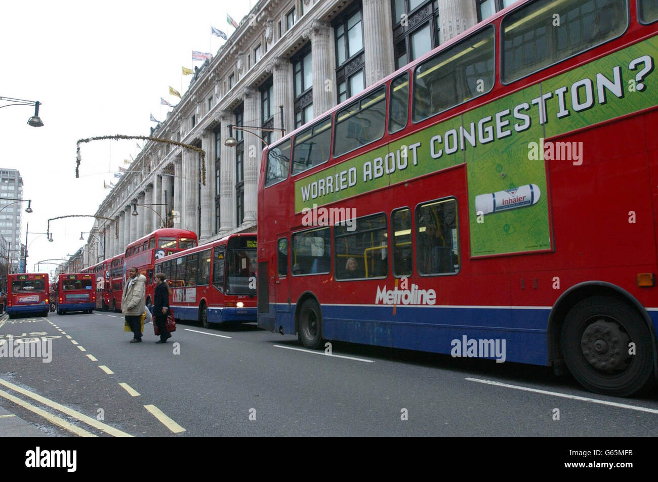 Buses line Oxford Street in London as a couple cross the road on the ...