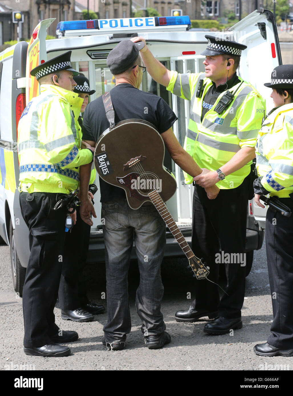 Alan Smart is led away by police after performing with his guitar with ...