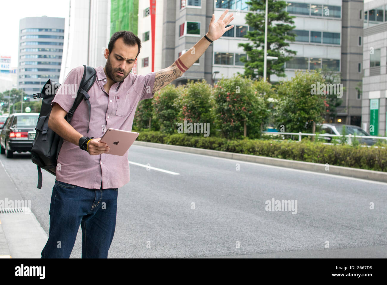 White man standing in road with cellphone hailing uber taxi Stock Photo ...