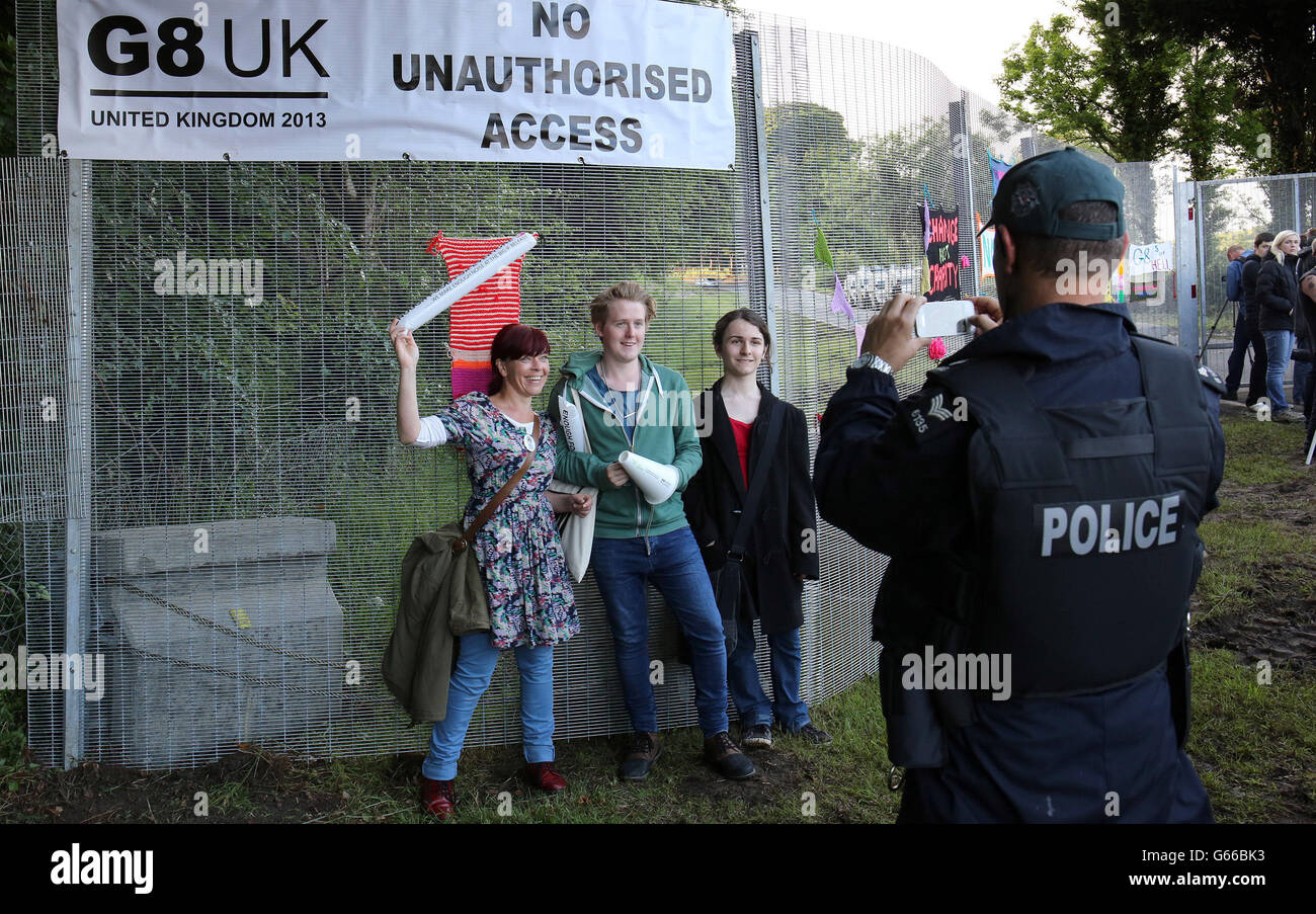 A police officer guarding security fence takes a photograph for ...