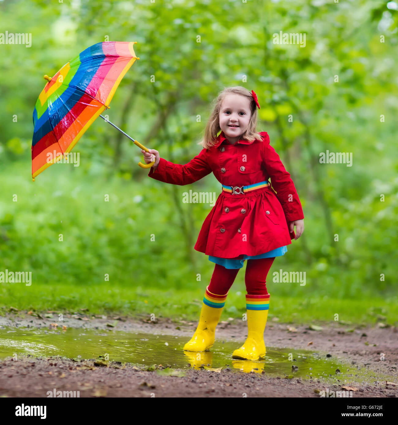 Little girl playing in rainy summer park. Child with colorful rainbow ...