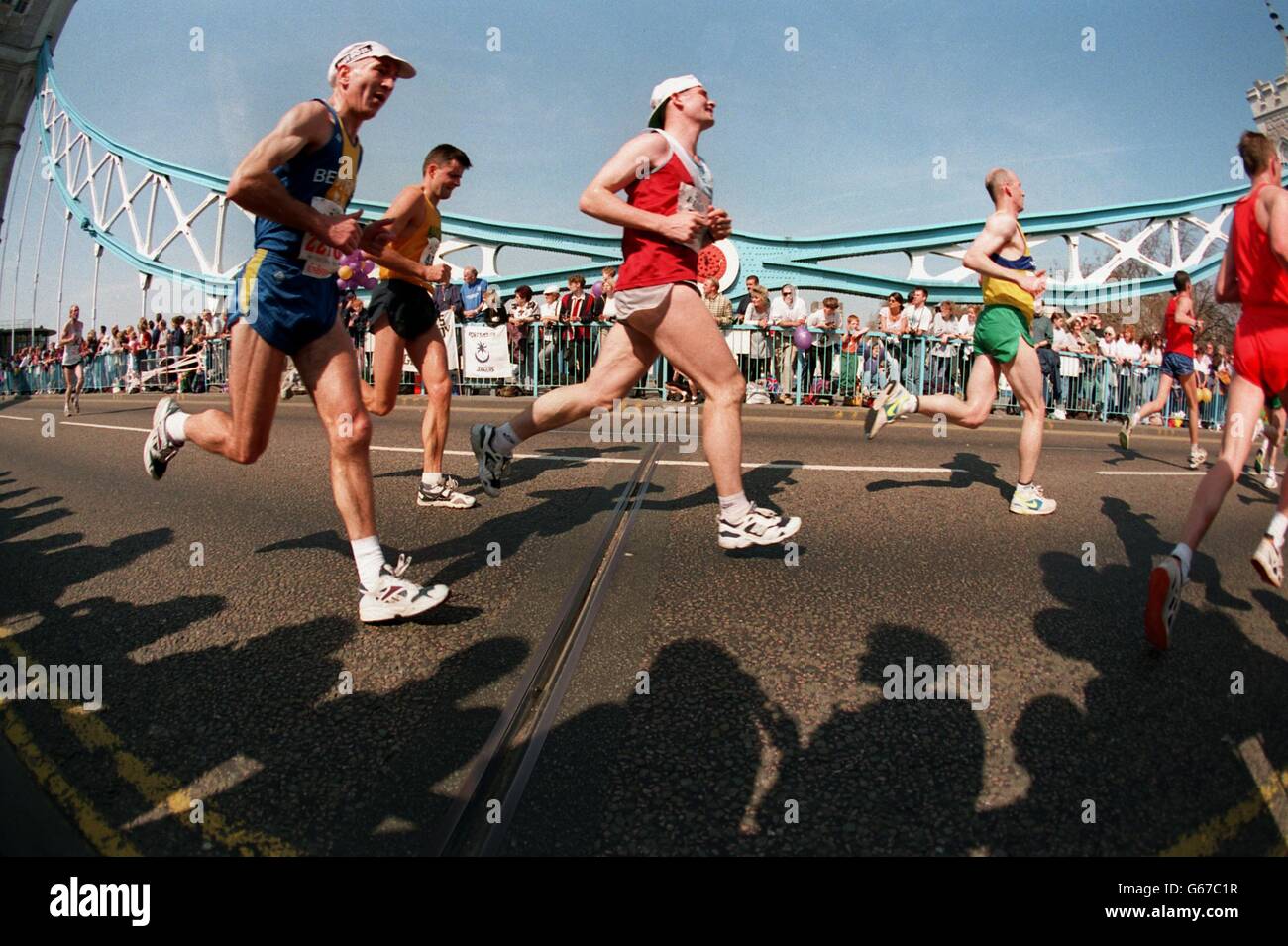 Runners pass over tower bridge shadows hi-res stock photography and ...