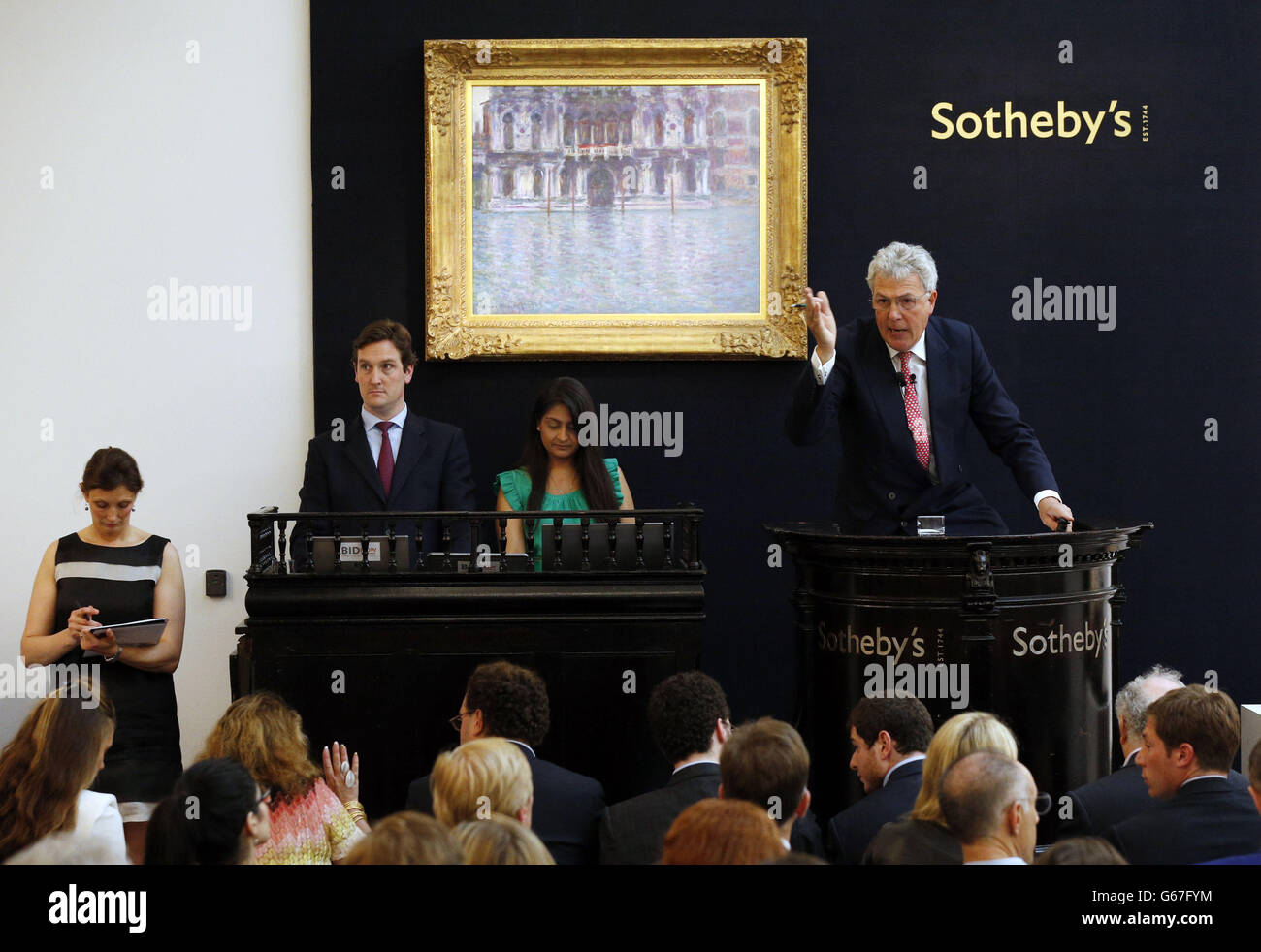 An auctioneer accepts bids whilst stood in front of Claude Monet's 'Le ...