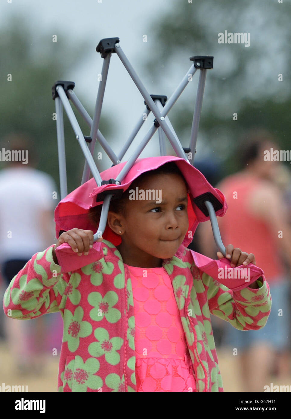 Aisha Thomas, five, from Shepton Mallet stands under a chair as rain ...