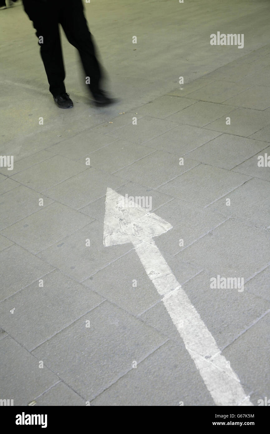 Arrow pointing towards man walking Stock Photo - Alamy