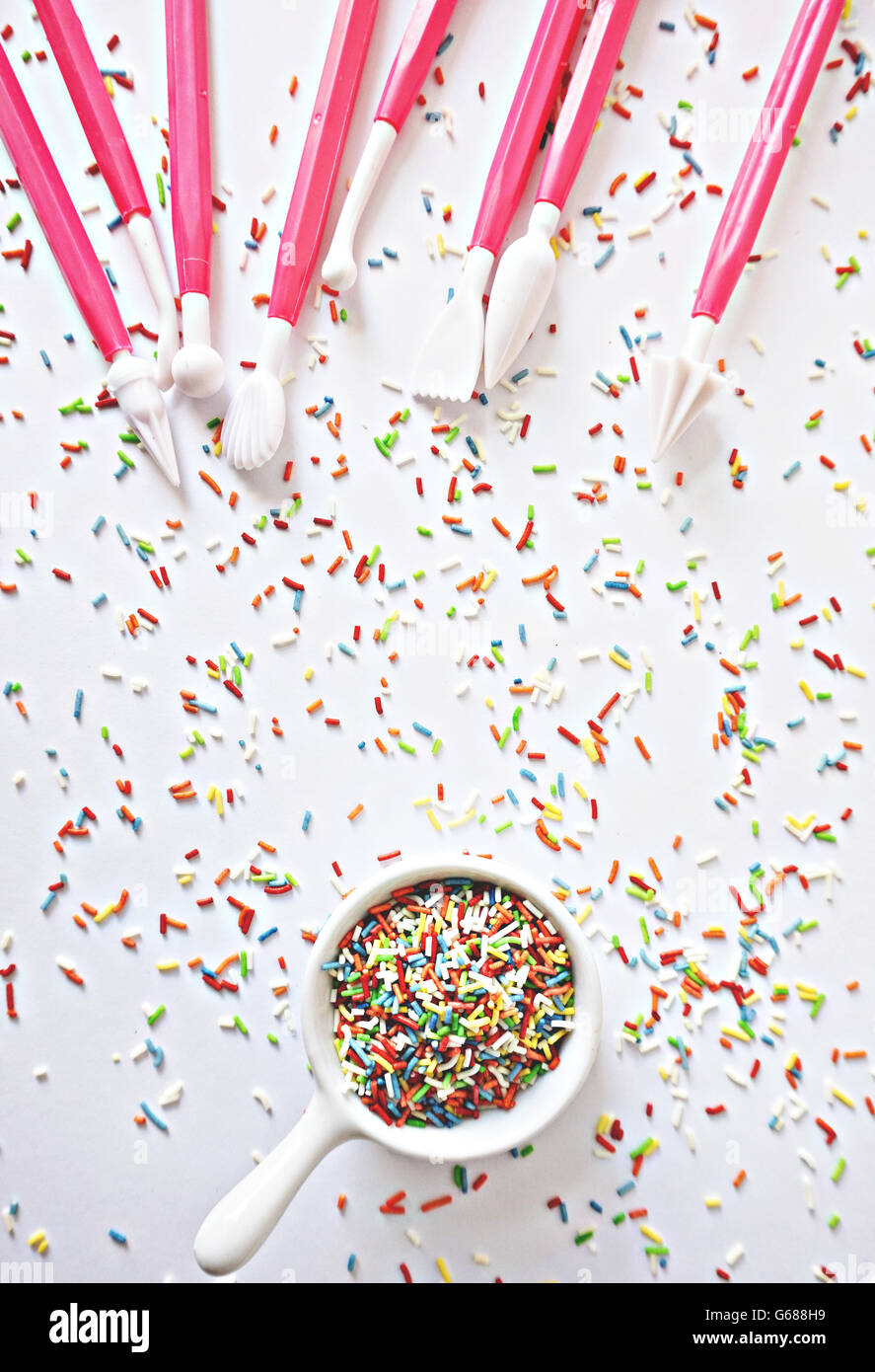 Cenital of sprinkles and cake's decoration tools in a white background ...
