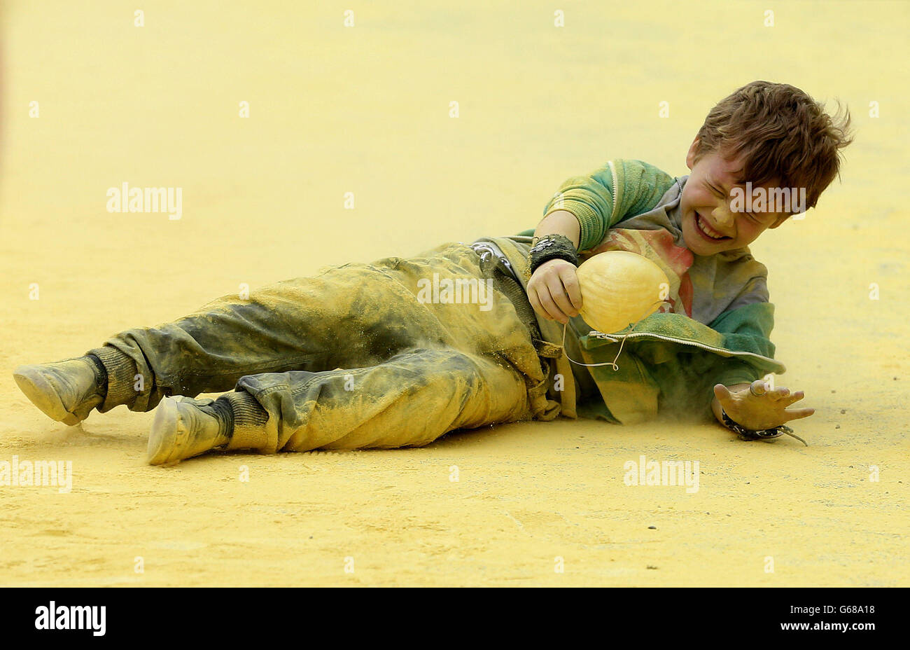A young boy rolls in yellow paint during the 5k Colour Run outside the ...