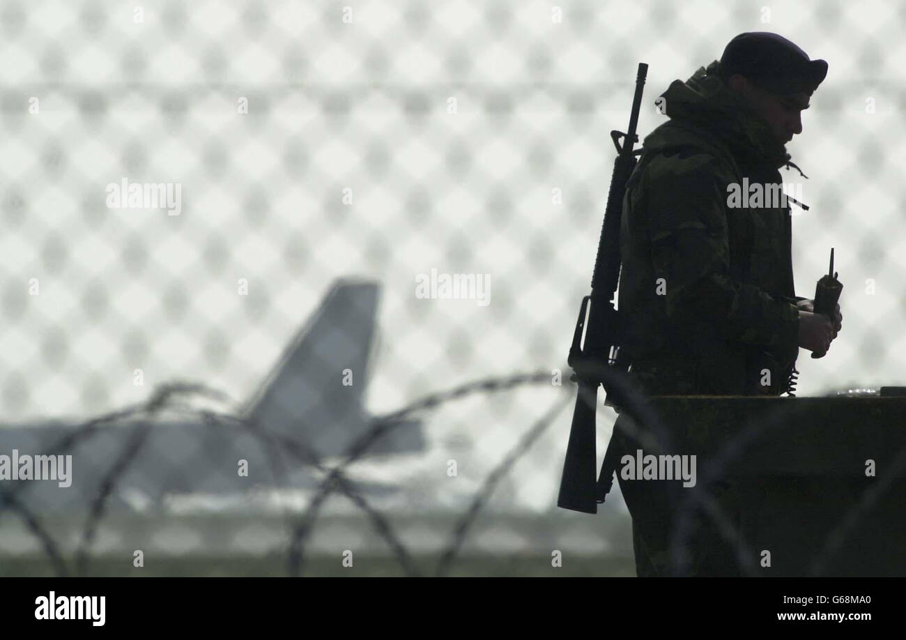 An armed American serviceman patrols the perimeter fence at RAF ...