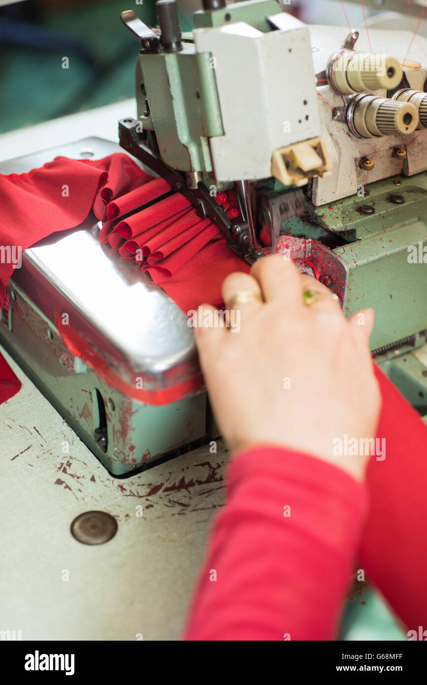 Hands of a seamstress sewing red cloth on a machine Stock Photo - Alamy