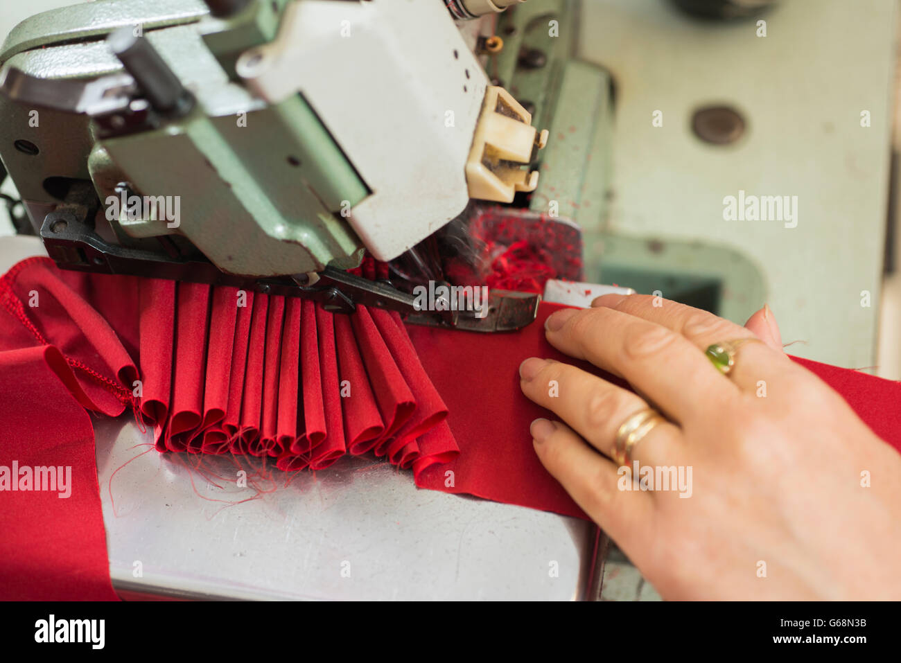 Hands of a seamstress stitching red cloth on sewing machine Stock Photo ...