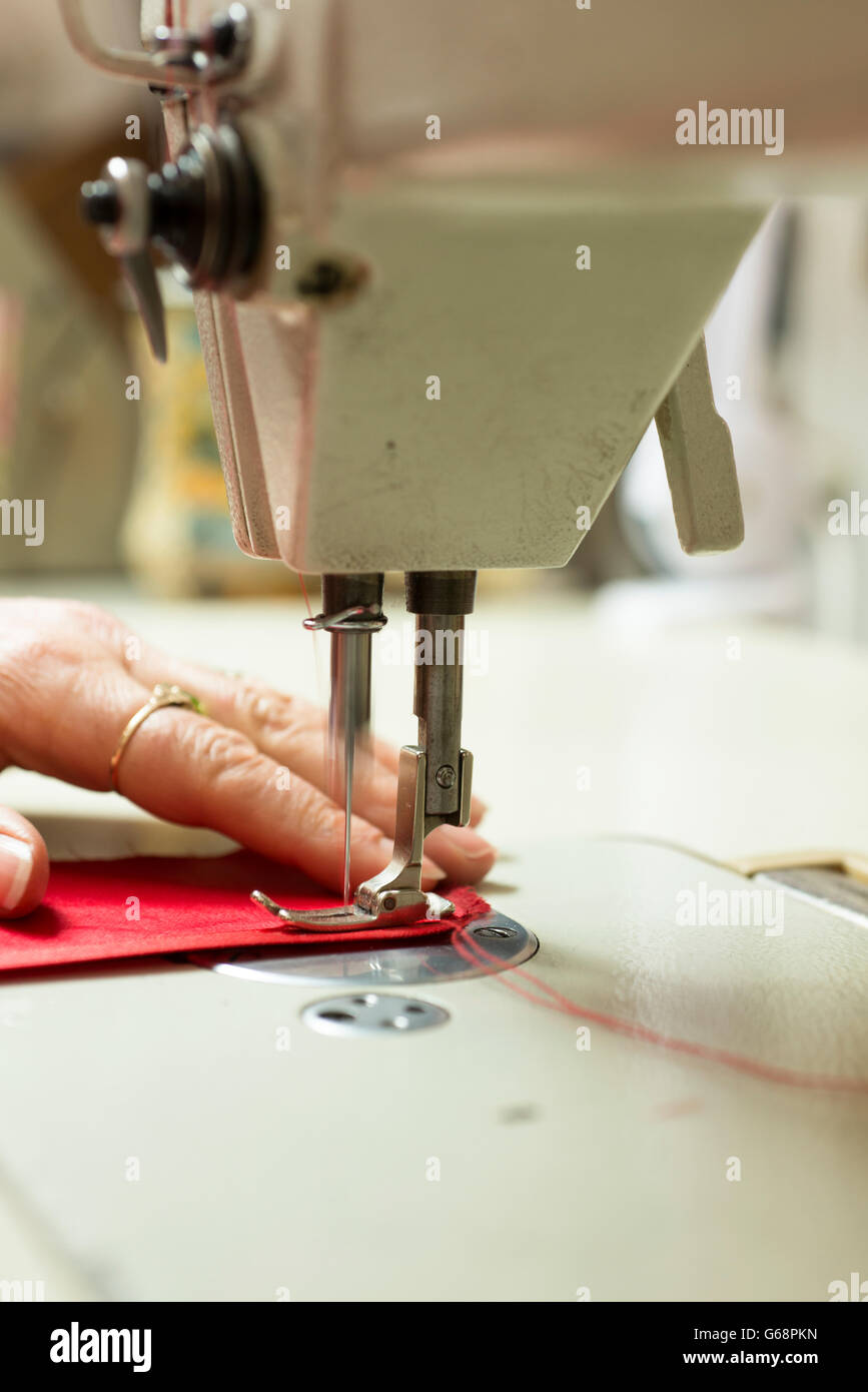 Motion blur of sewing machine needle stitching red cloth with tailor's ...