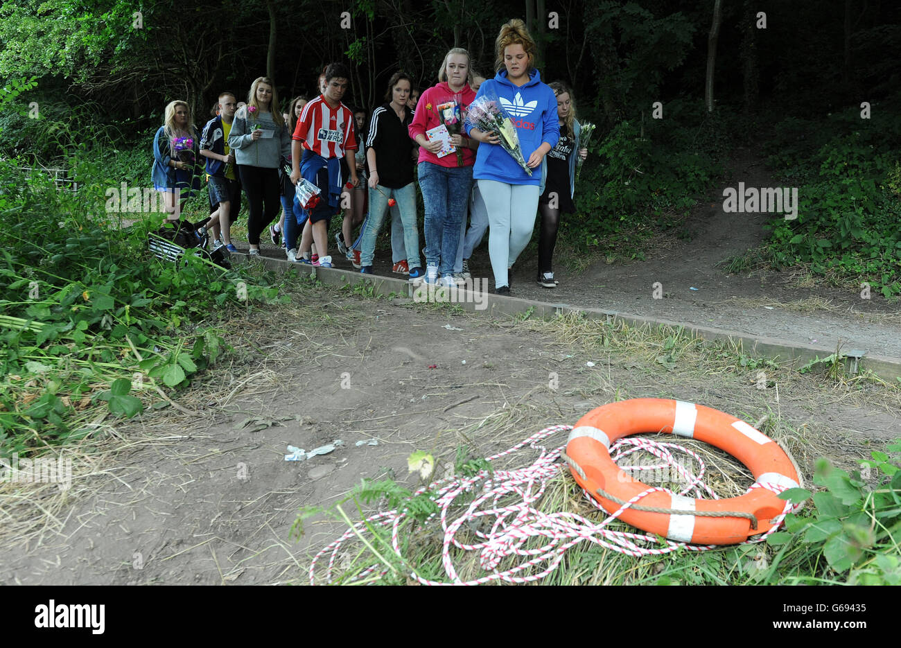 Friends of the two teenagers who drowned throw flowers in the river ...