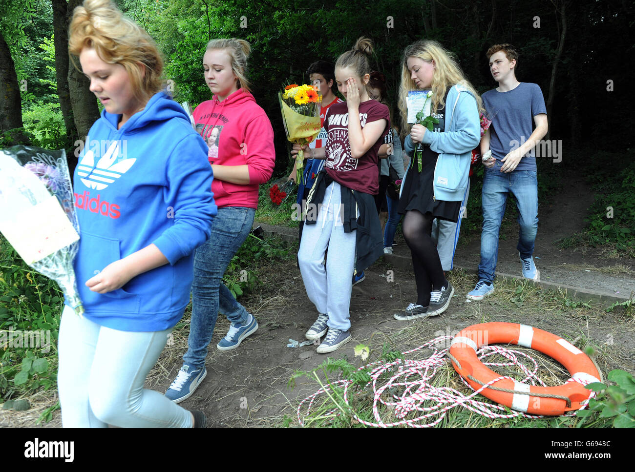 Friends of the two teenagers who drowned throw flowers in the river ...
