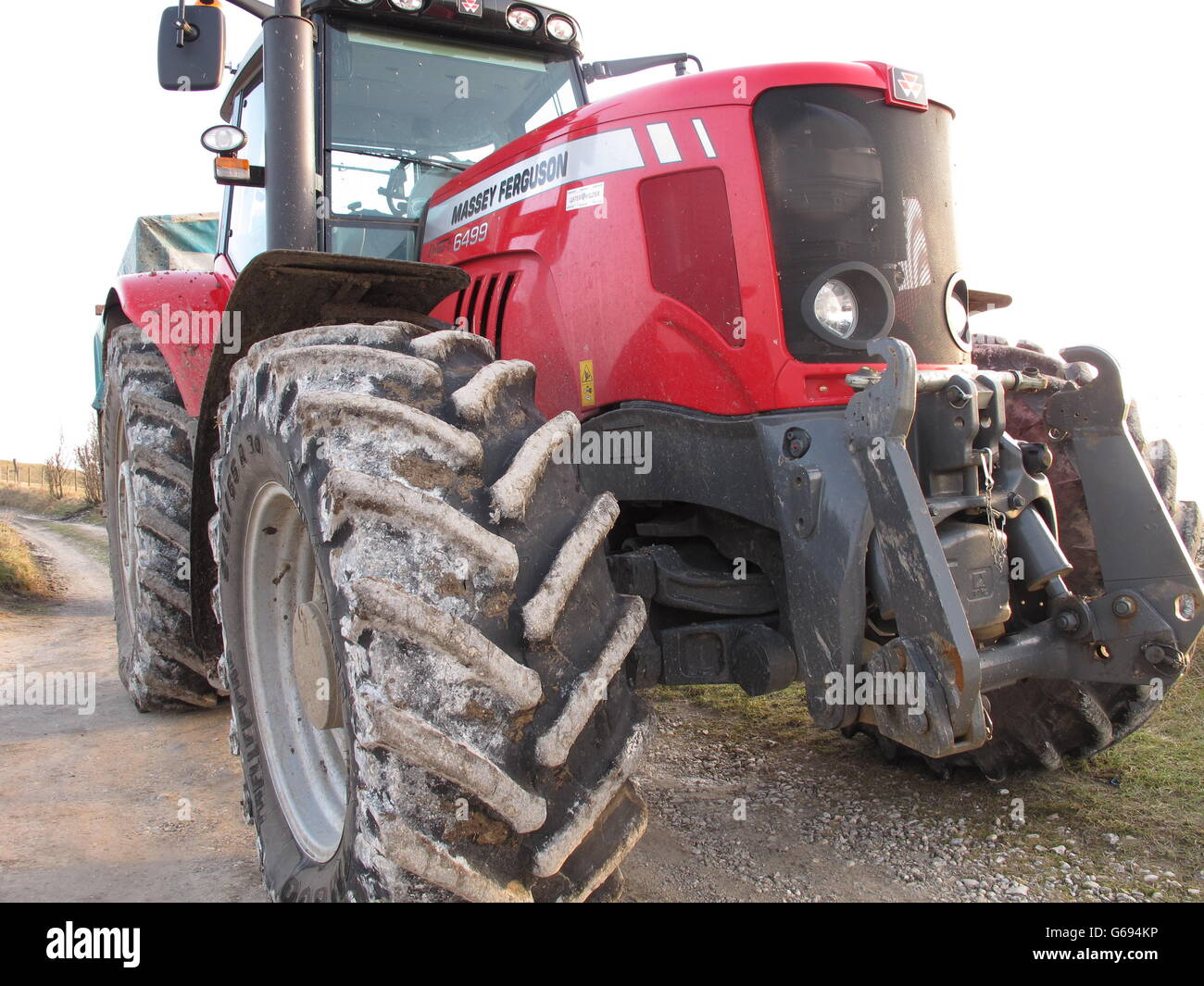 Huge dirty red farm tractor covered in white chalk soil of the North ...
