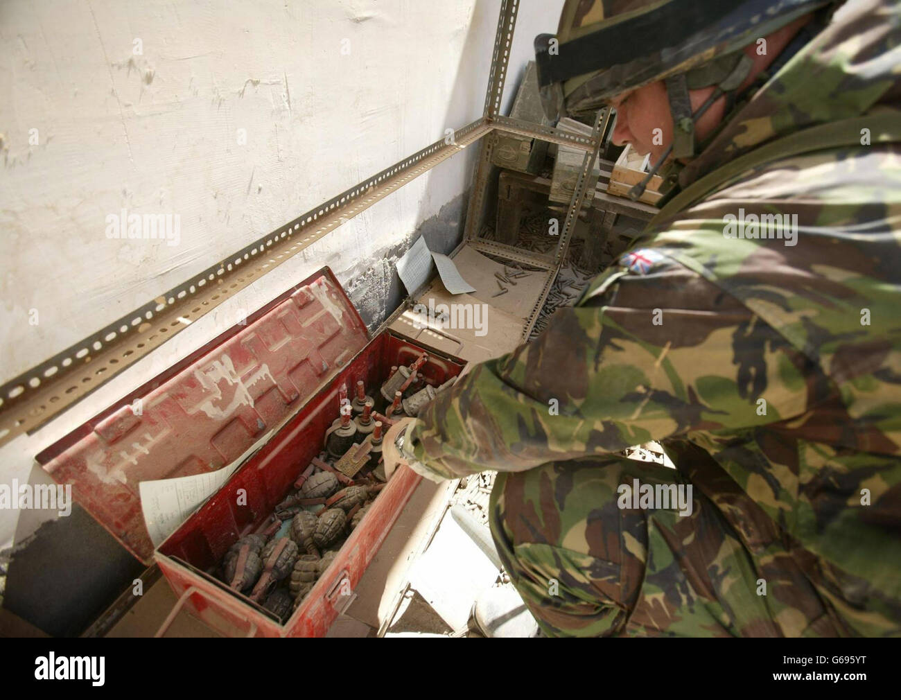 An Irish Guardsman examining hand grenades left on an abandoned Iraqi ...