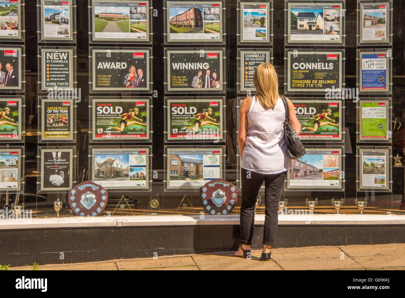 A female looking in an estate agents shop window Stock Photo - Alamy