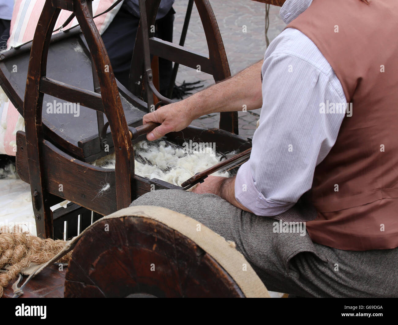 Elder carder while carding wool or cotton with old wooden machine in ...