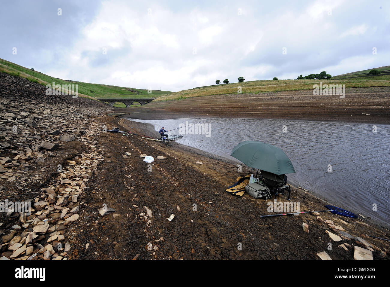 A man fishes in Dowry Reservoir near Oldham, as the water levels recede ...