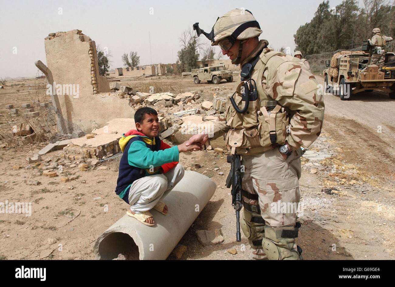 A US soldier shakes hands with a curious Iraqi boy at the Iraq border ...