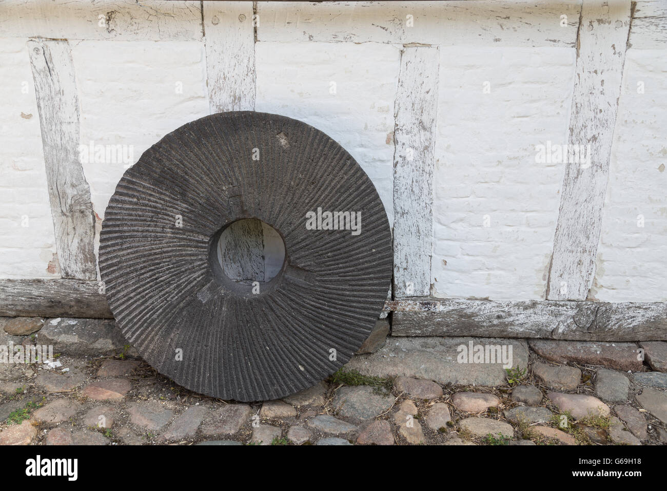 An old millstone standing on a wall Stock Photo - Alamy