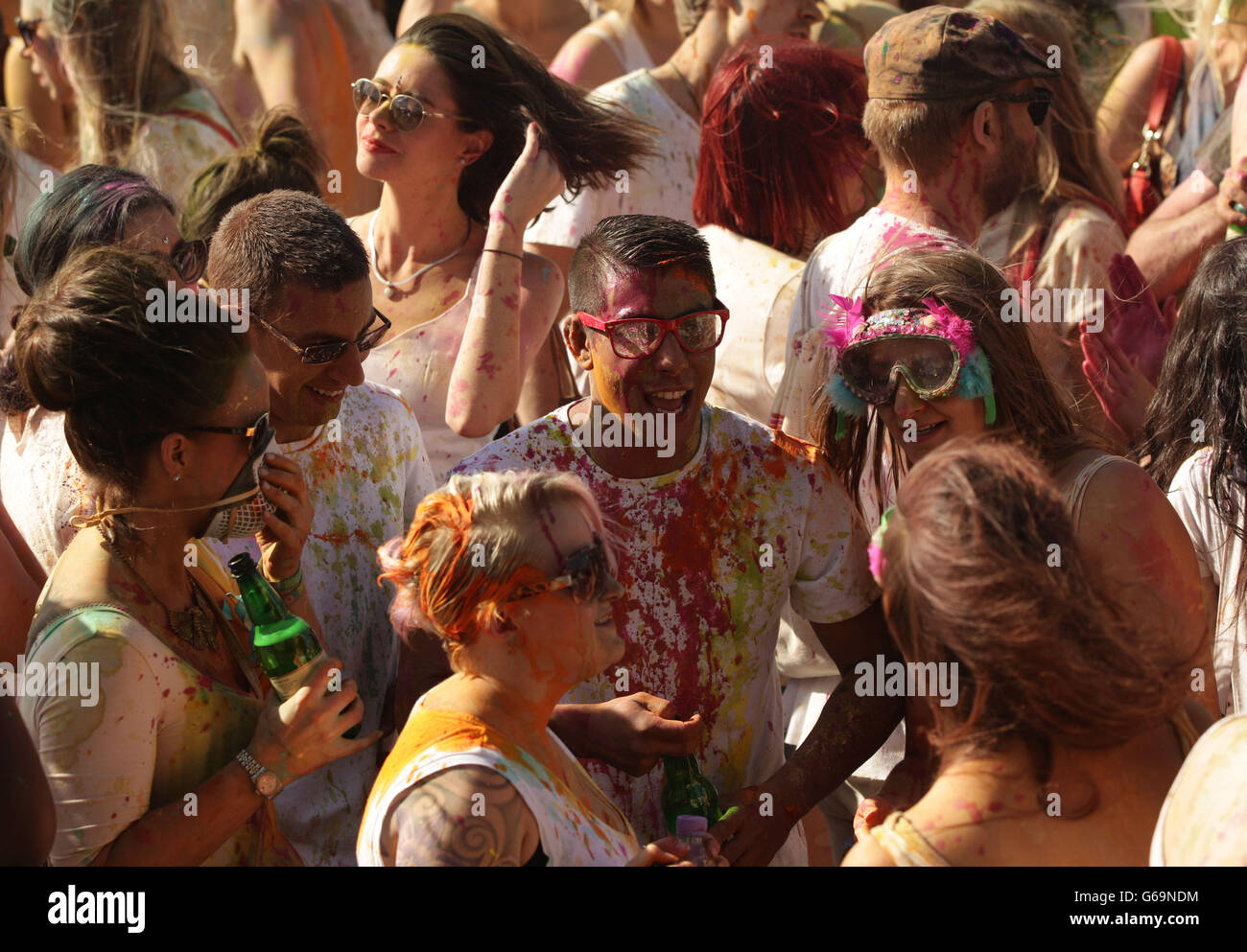 People covered in a brightly coloured powder thrown in the air during the Holi One Festival, at ...