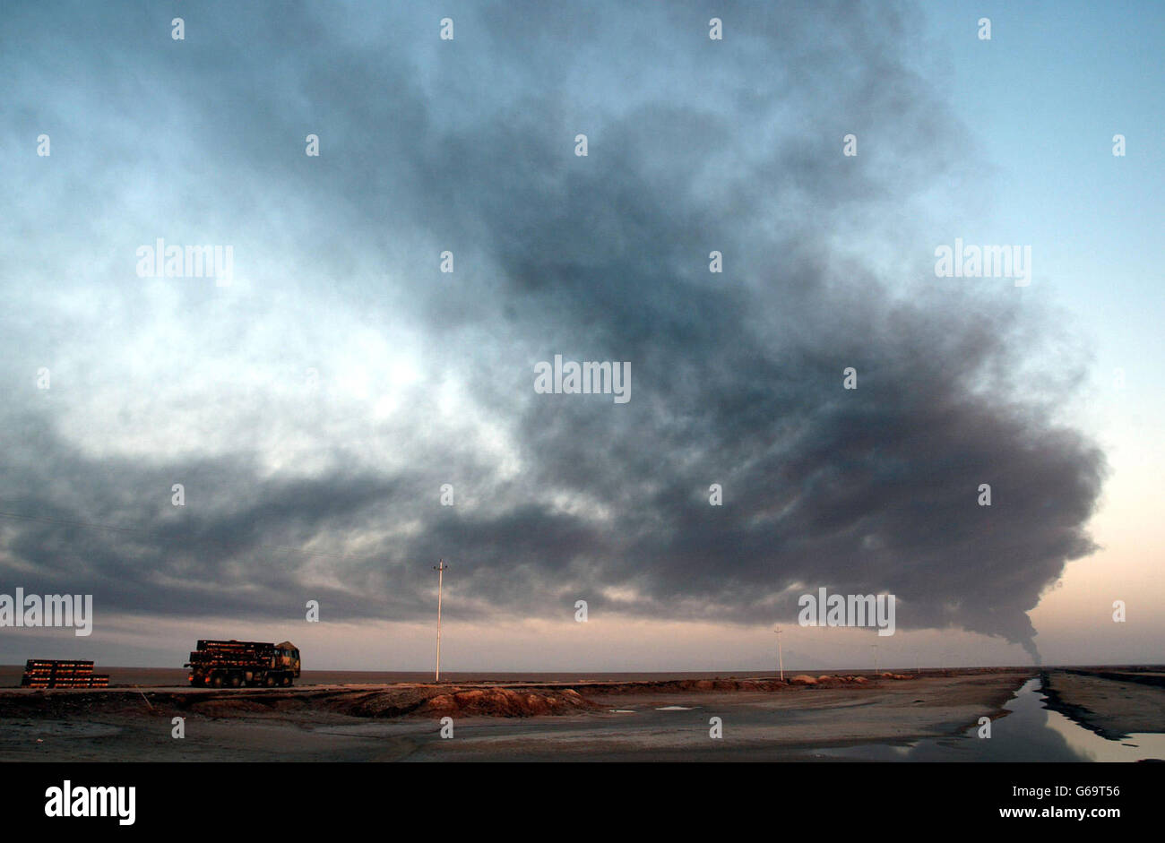 An oil fire burns, blackening the sky south of Basra in Southern Iraq ...
