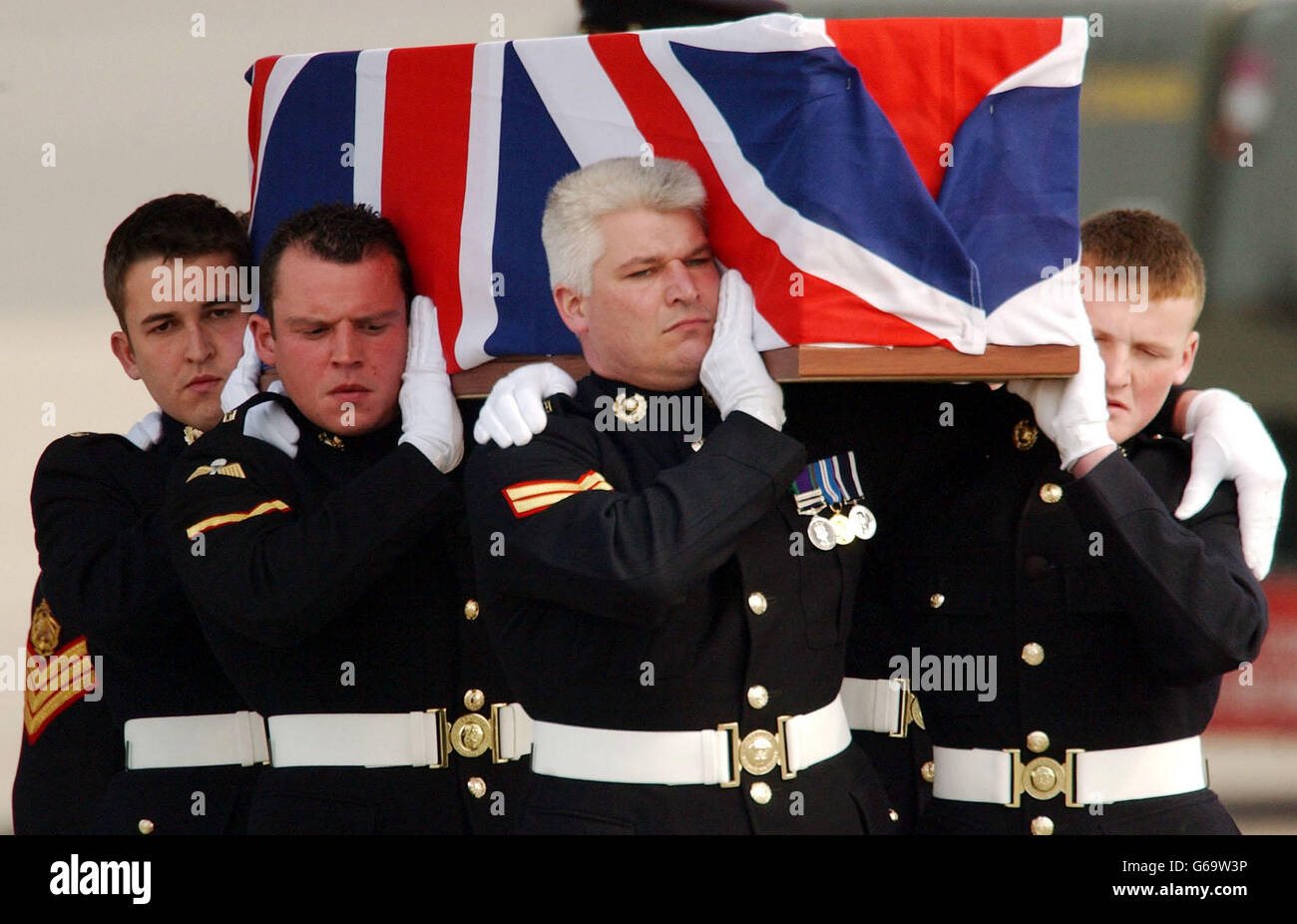 Royal Marines carry one of their number from an RAF transport plane ...