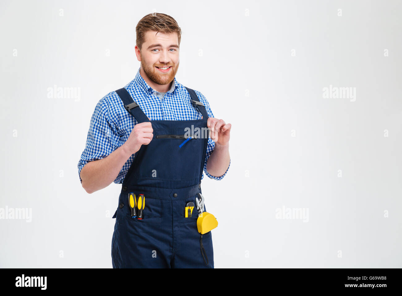 Smiling handsome male builder standing isolated on a white background ...