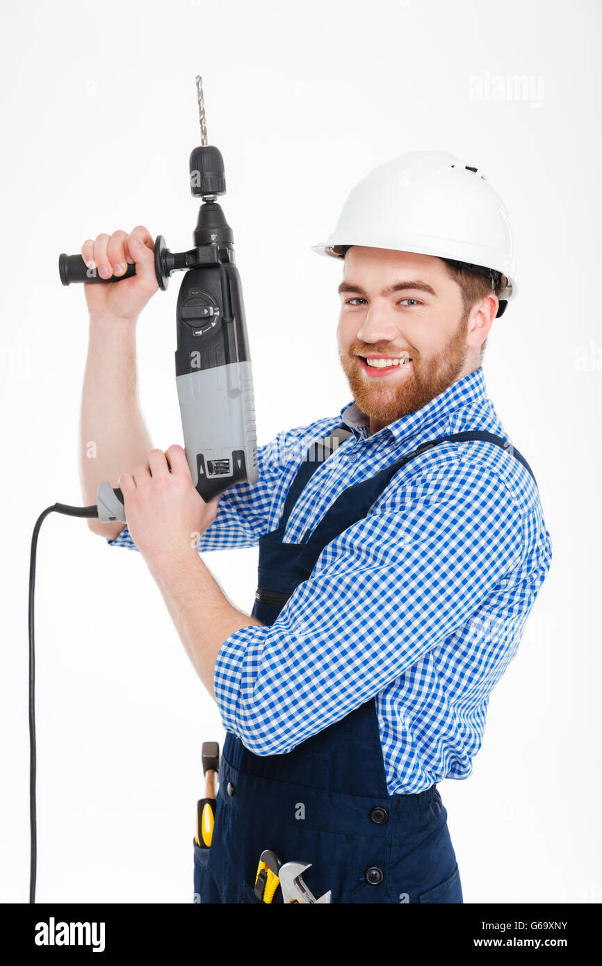 Happy attractive young worker standing and smiling using drill Stock ...