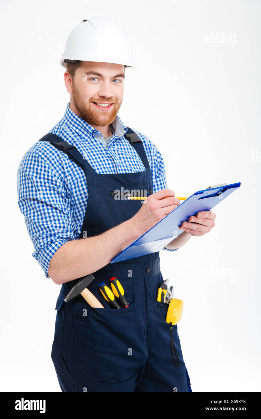 Happy confident young builder writing and using clipboard Stock Photo ...