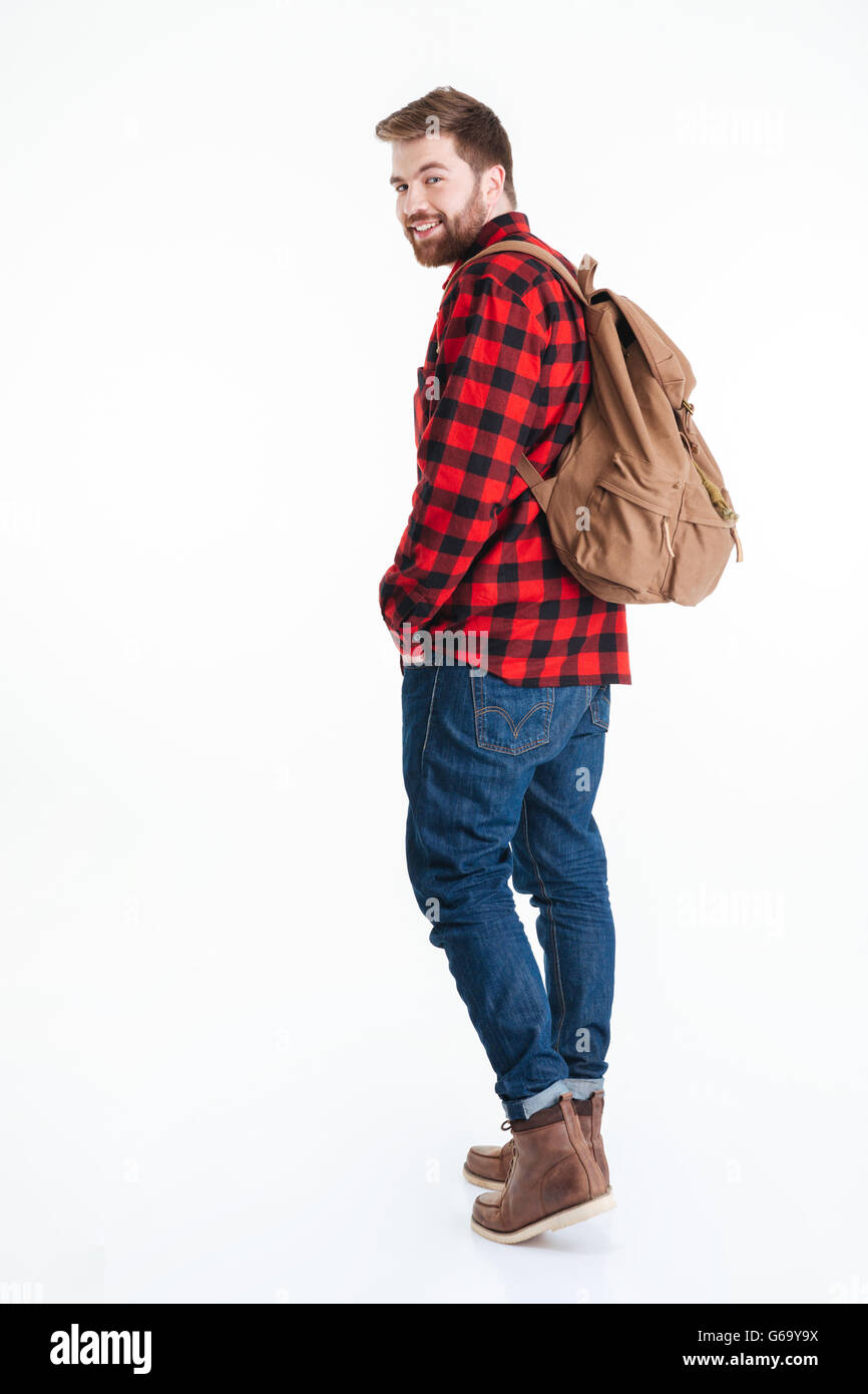 Full length portrait of a casual man looking back at camera isolated on ...