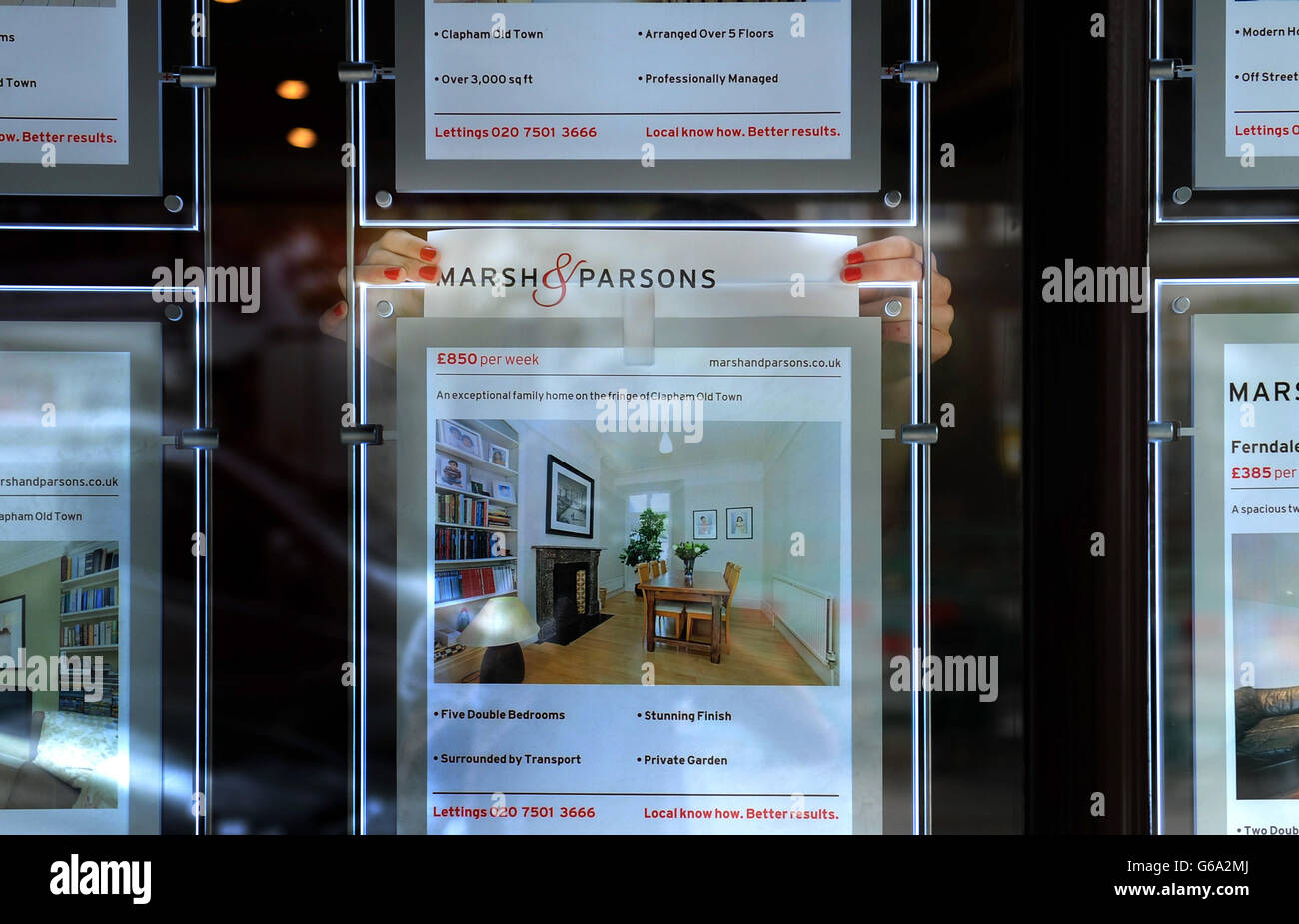 Property stock. An Estate Agent hangs property details in the window in ...