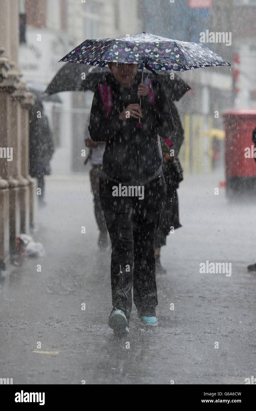 People get caught in a rain shower near Barbican station in central ...