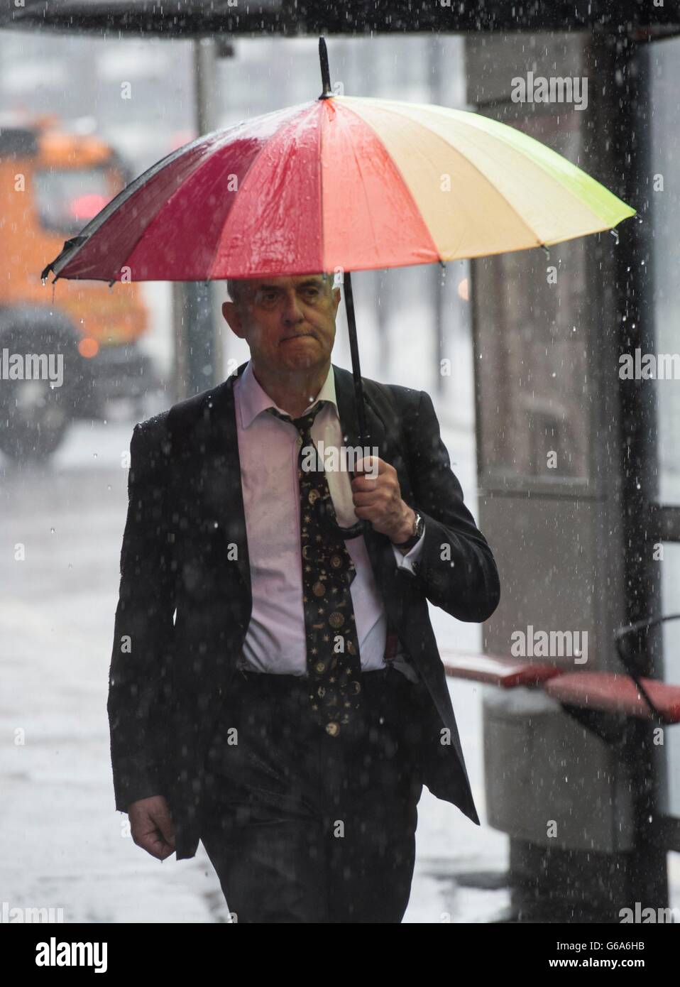 A man gets caught in a rain shower near Barbican station in central ...