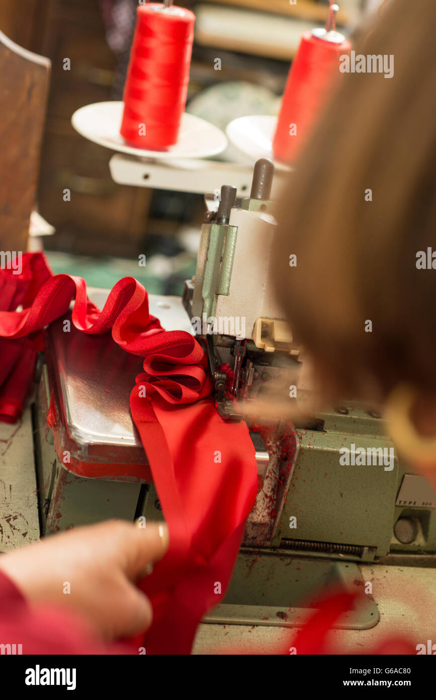 Red cloth being ruffled through a sewing machine by seamstress Stock ...