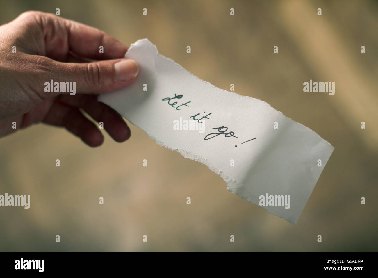 Hand holding a note of paper with the message let it go written on it ...
