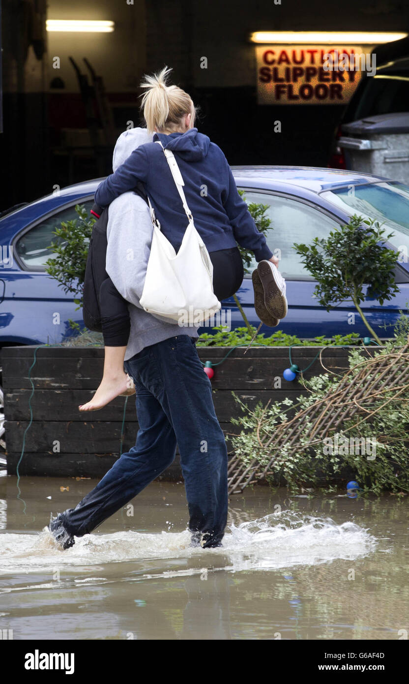 A man helps a lady through the water on Half Moon Lane in Herne Hill ...