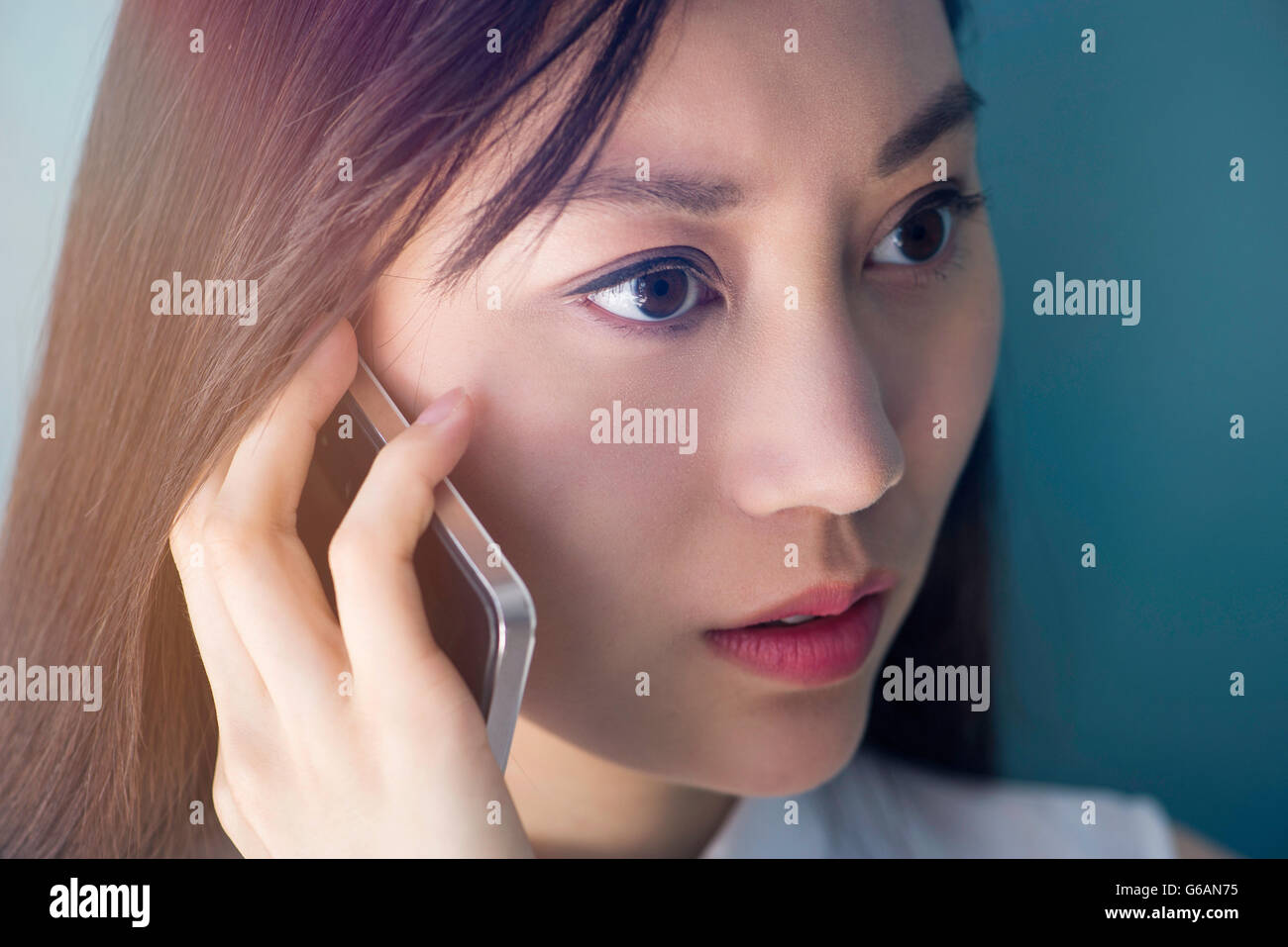 Woman listening to cell phone with serious expression Stock Photo - Alamy