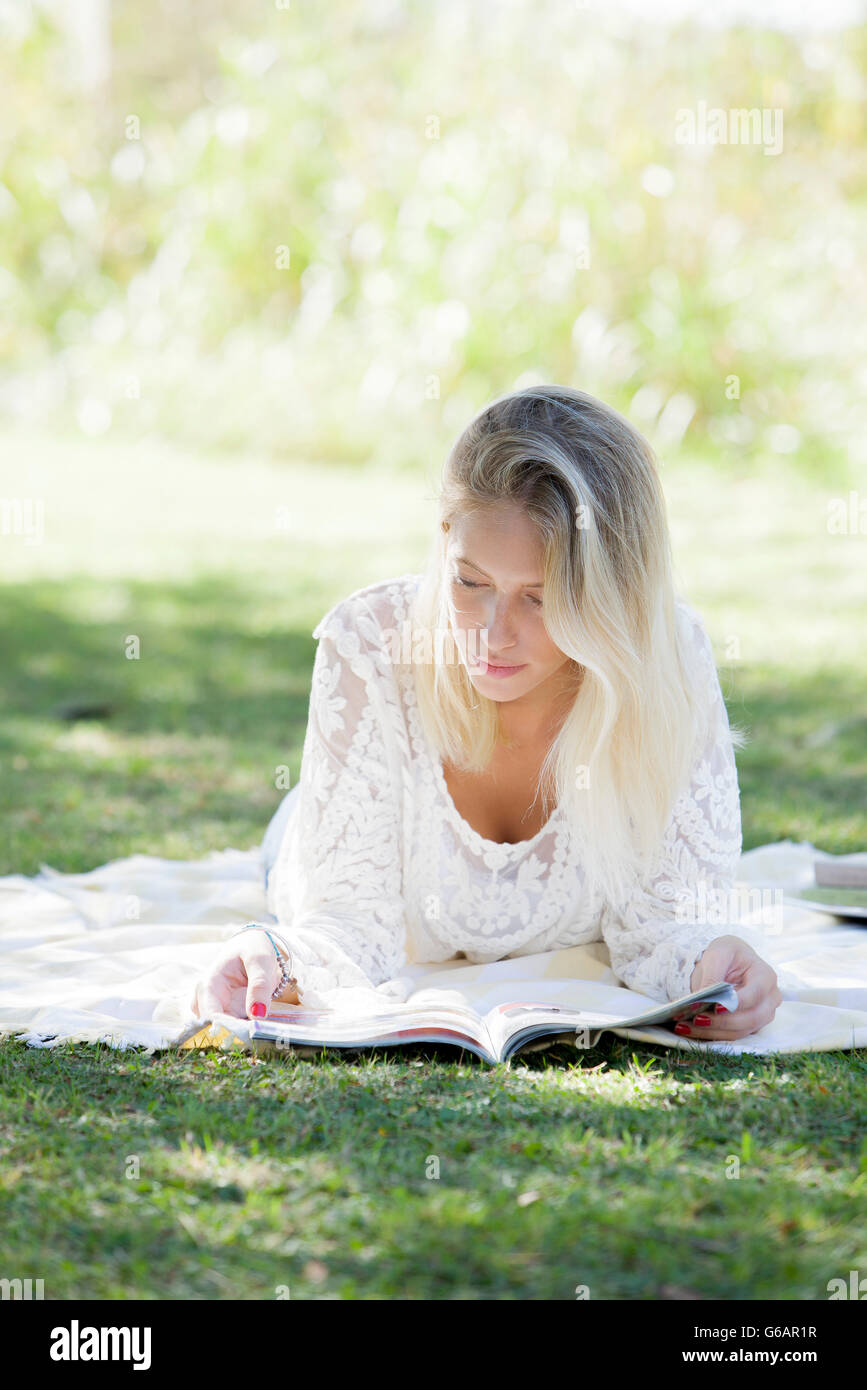 Woman reading magazine in park Stock Photo - Alamy